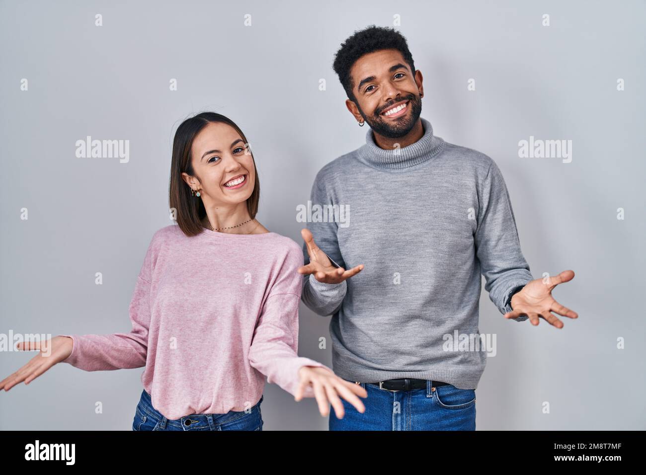 Young hispanic couple standing together smiling cheerful with open arms ...