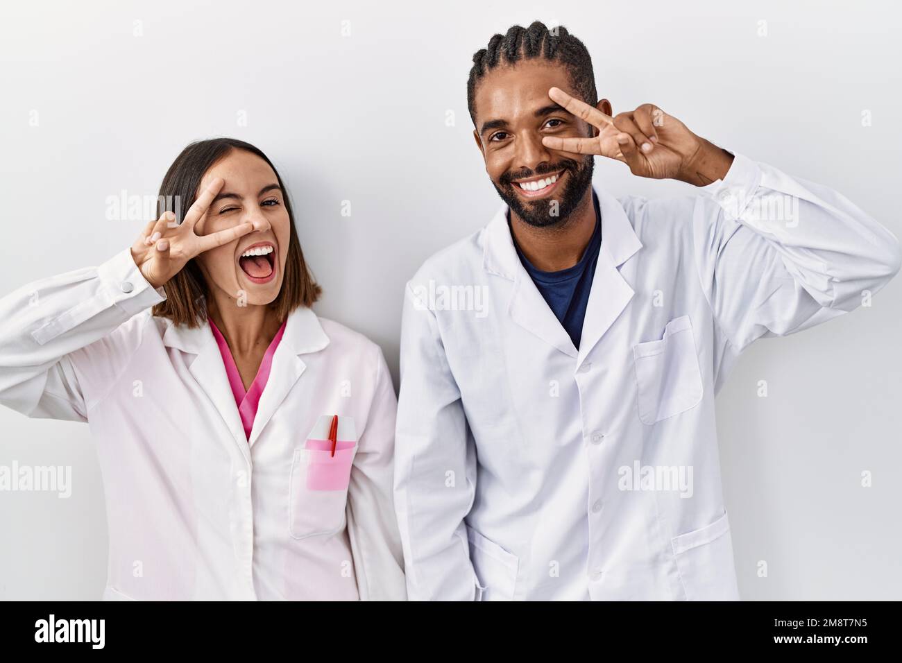 Young hispanic doctors standing over white background doing peace ...