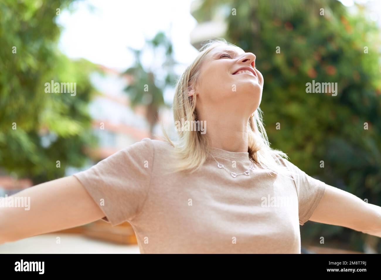 Young blonde woman breathing with arms open at park Stock Photo - Alamy