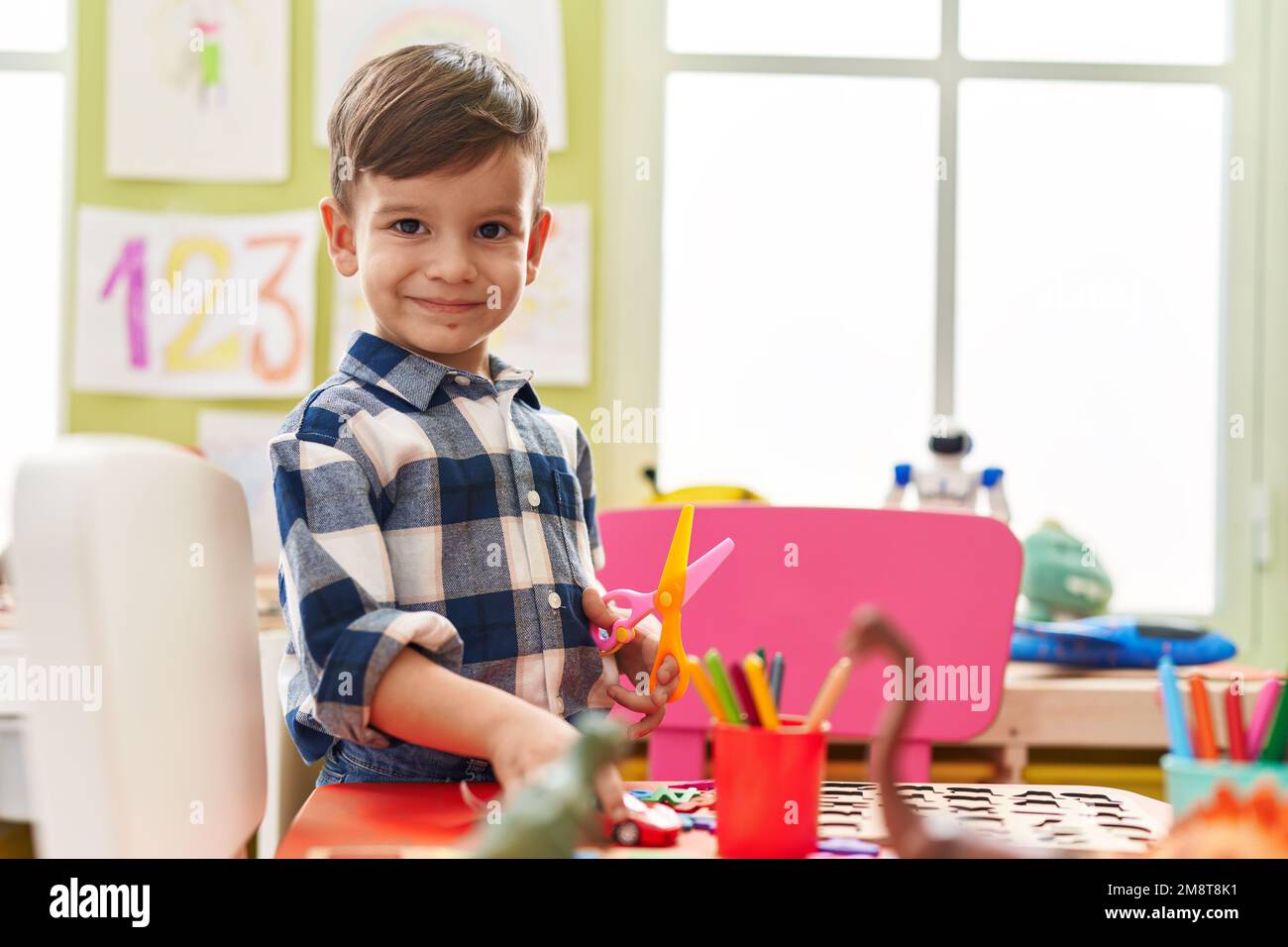 Adorable hispanic boy student smiling confident holding scissors at ...