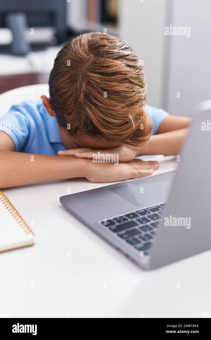 Adorable hispanic boy student using computer with stressed expression ...