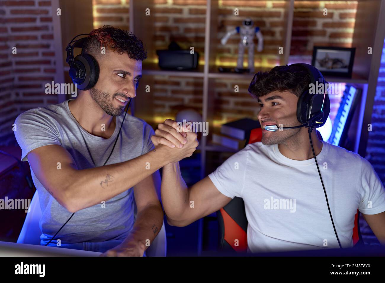 Two hispanic men streamers playing video game shake hands at gaming ...