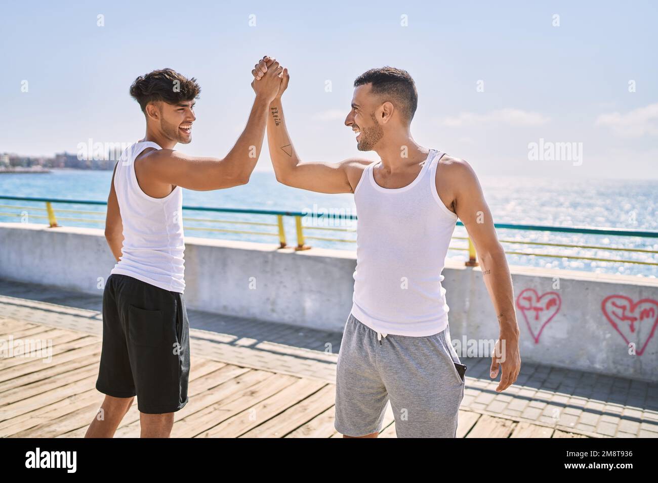 Two hispanic men couple smiling confident high five with hands raised ...
