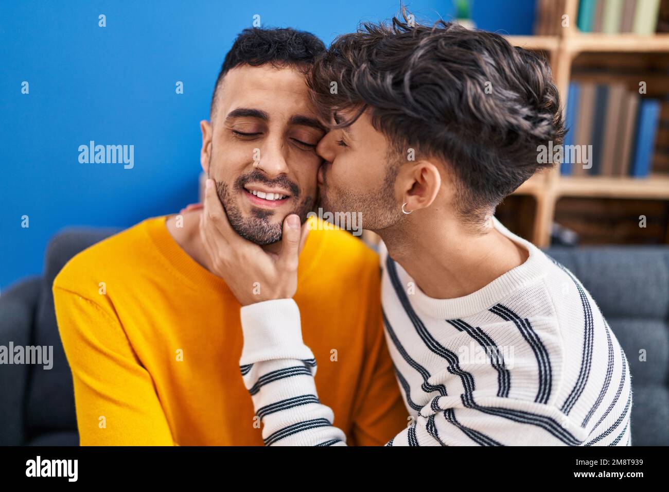 Two man couple hugging each other and kissing sitting on sofa at home Stock Photo - Alamy