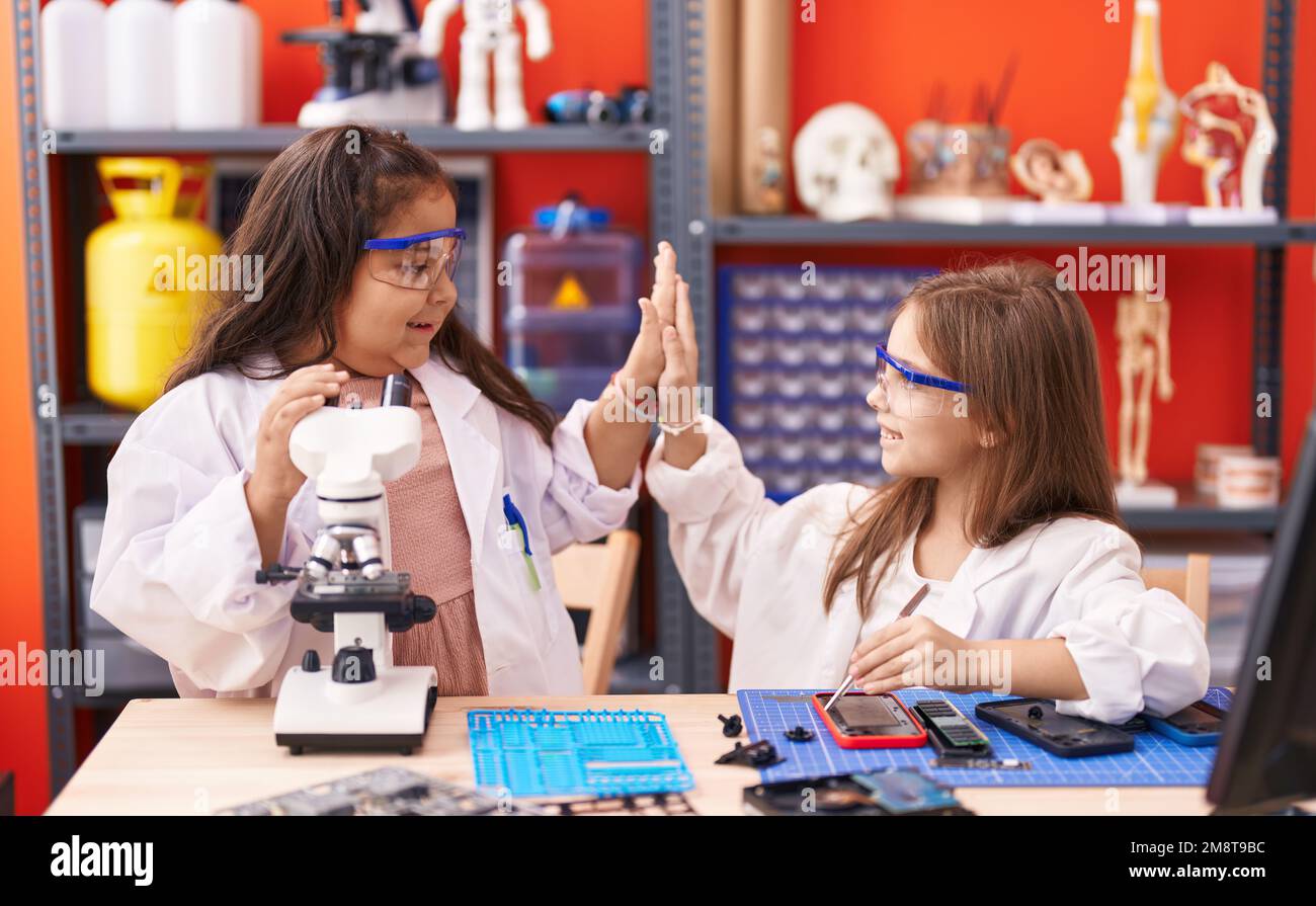 Two kids students high five with hands raised up at laboratory ...