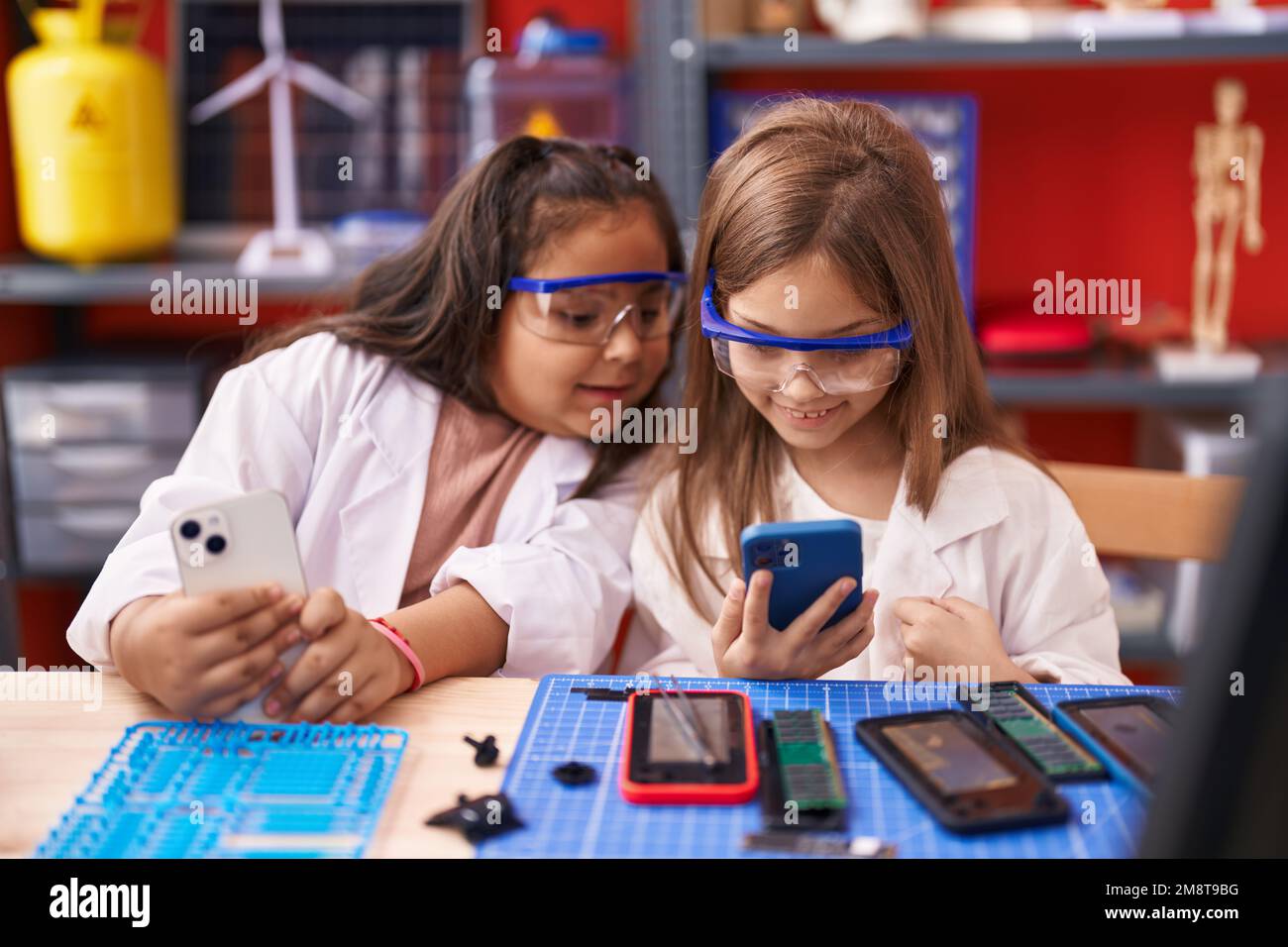 Two kids students using smartphones standing at laboratory classroom ...
