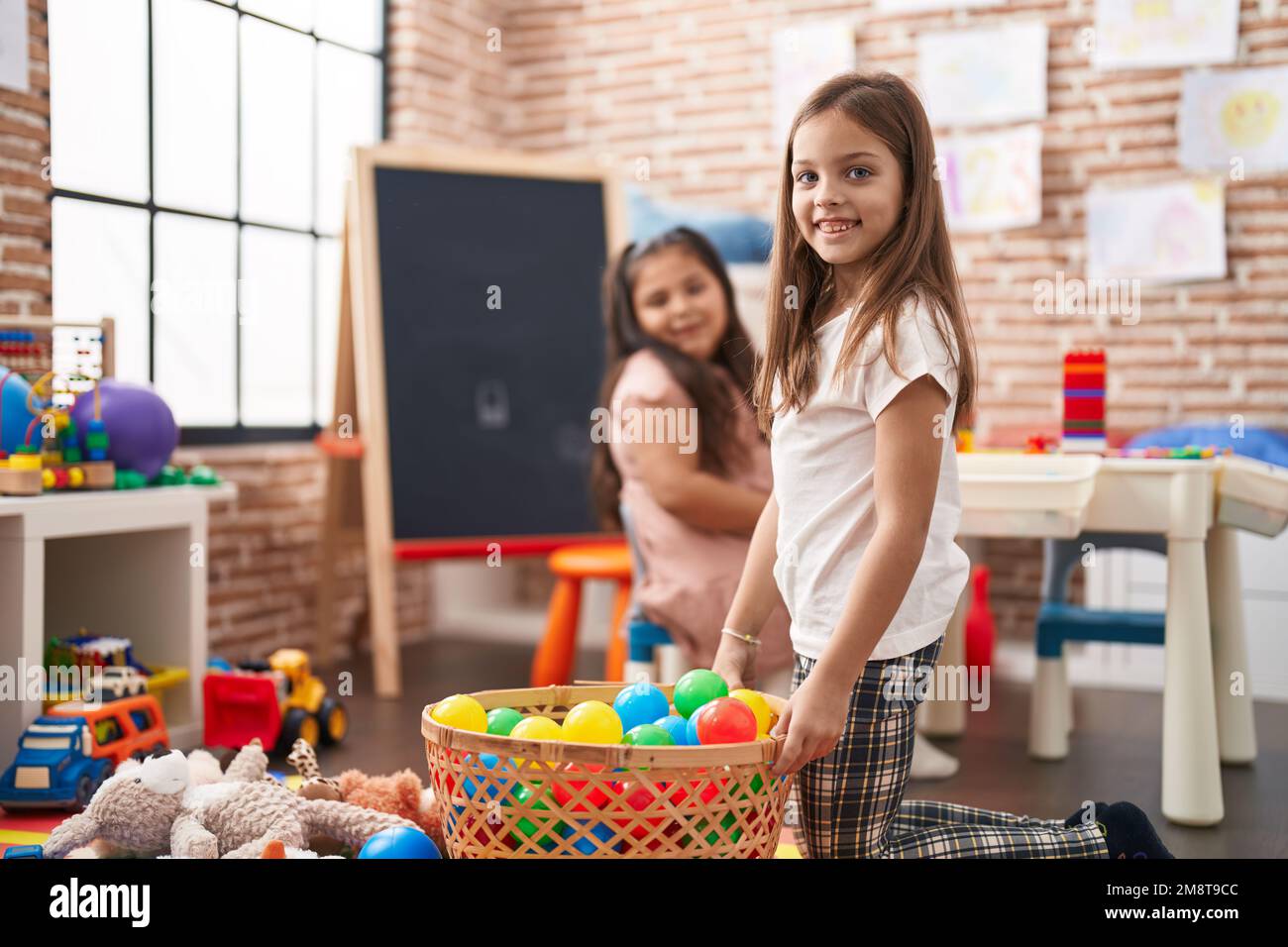 Two kids playing with balls sitting on floor at kindergarten Stock ...