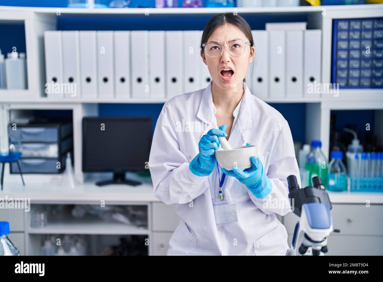 Chinese young woman working at scientist laboratory mixing angry and ...