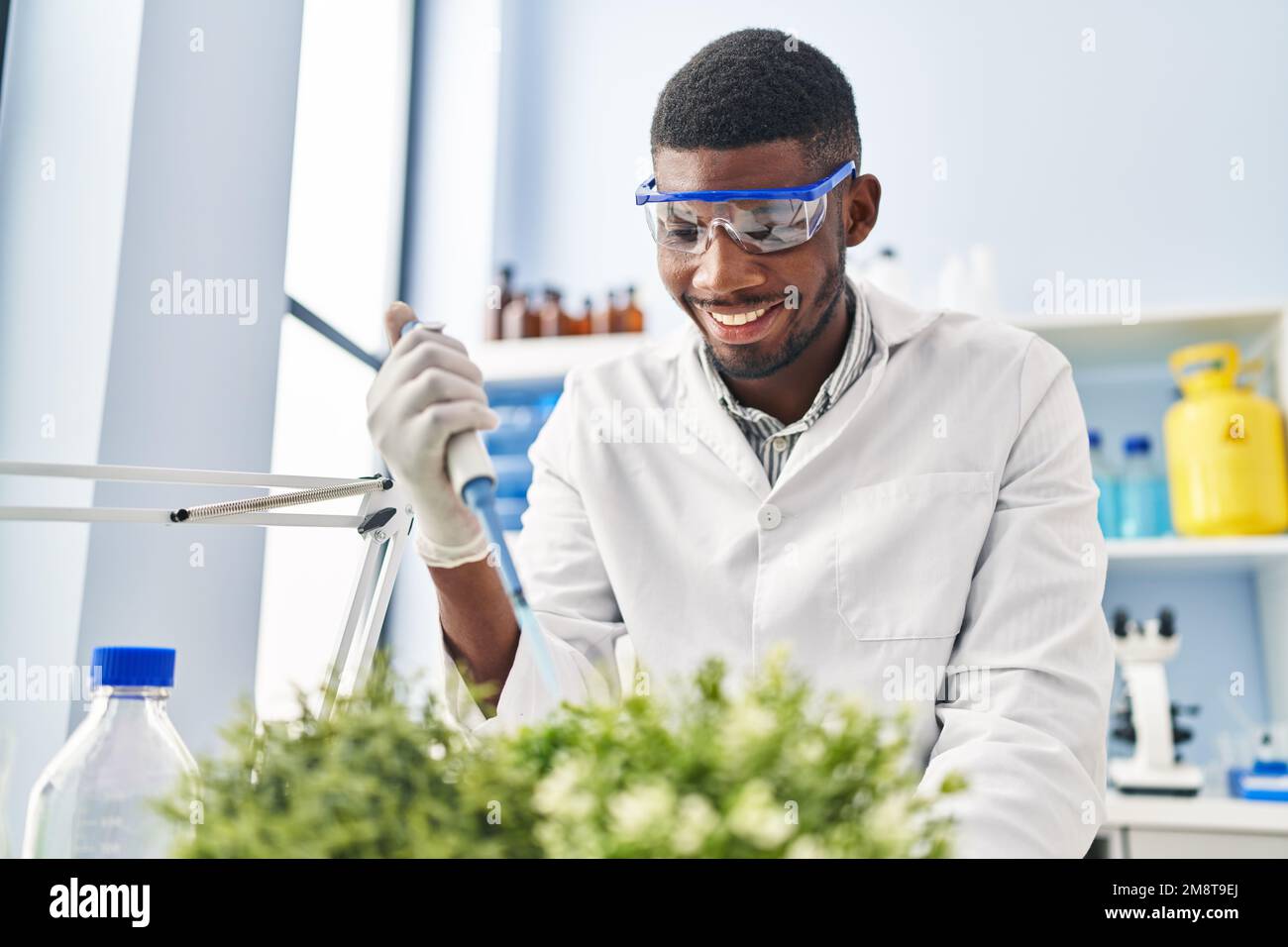 Young african american man wearing scientist uniform using pipette on ...