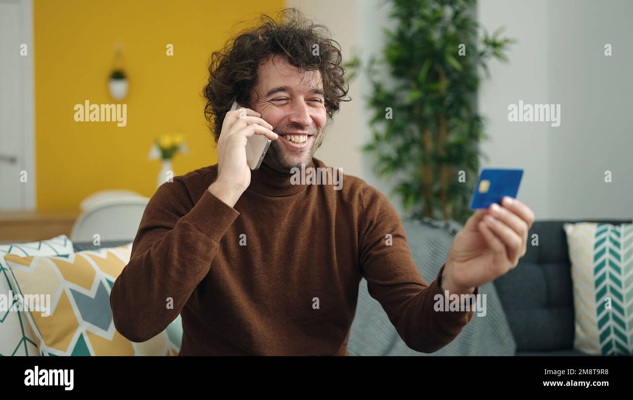 Young hispanic man talking on smartphone and credit card sitting on ...