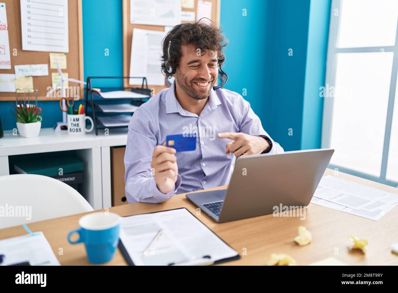 Hispanic young man working at the office doing online shopping smiling ...