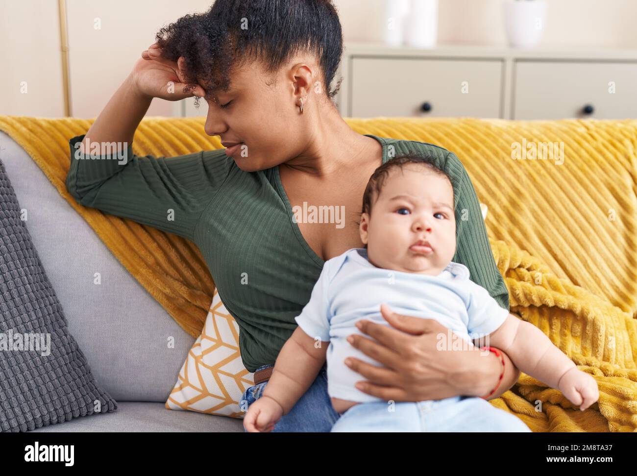 Mother and son sitting on sofa with tired expression at home Stock ...