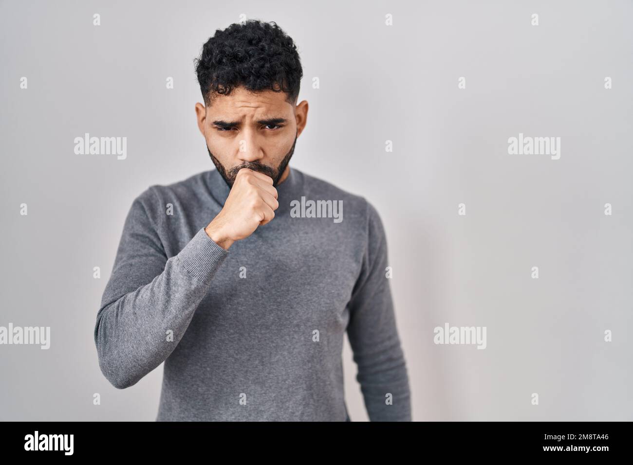 Hispanic man with beard standing over white background feeling unwell ...
