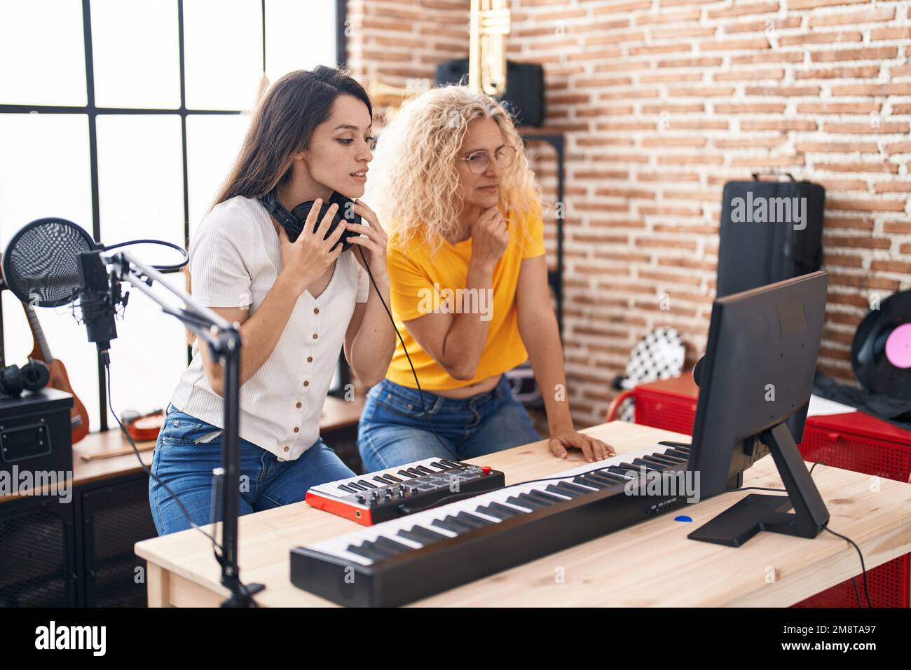 Two women musicians composing song using keyboard at music studio Stock ...