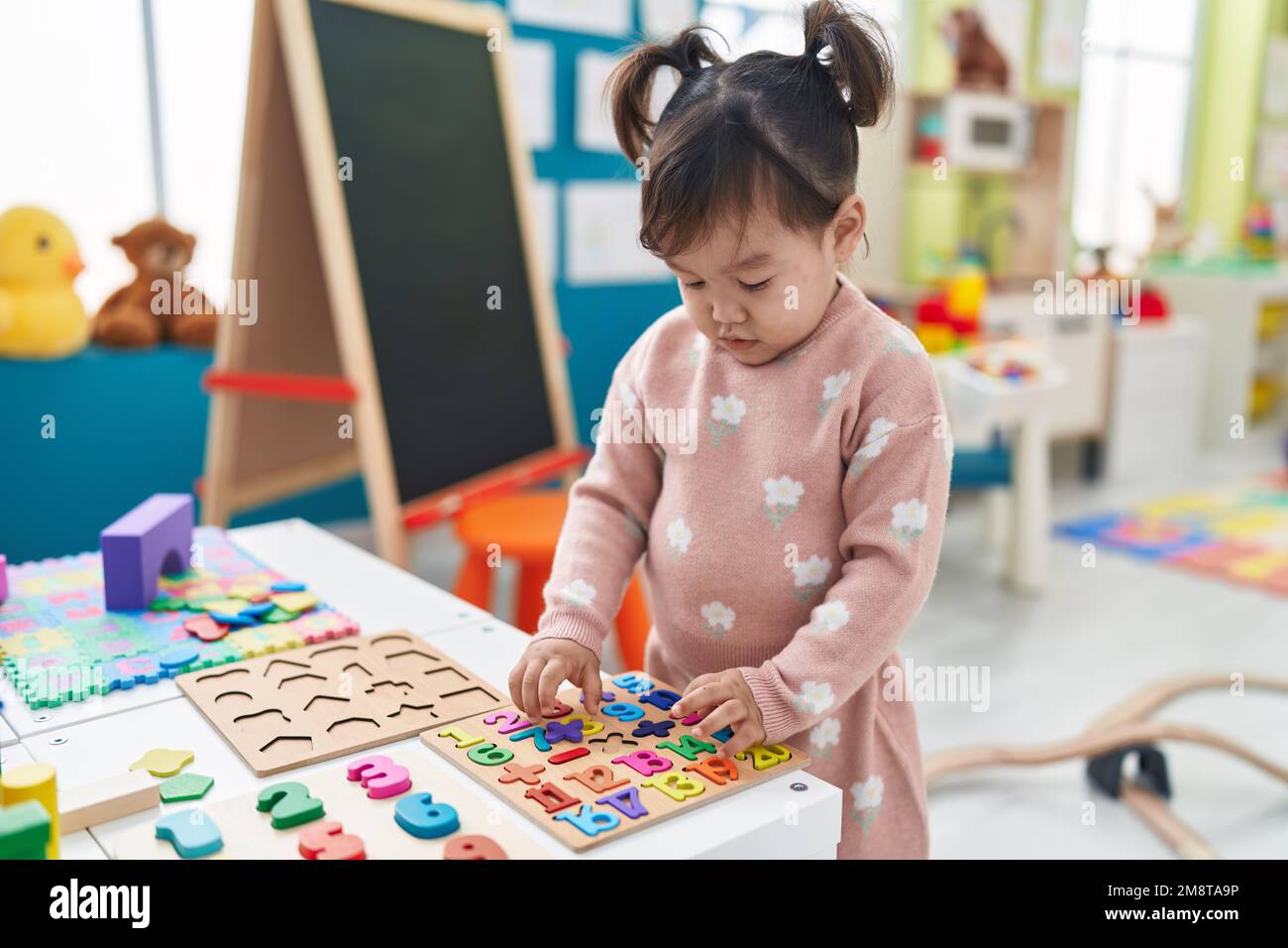 Adorable chinese girl playing with maths puzzle game standing at ...