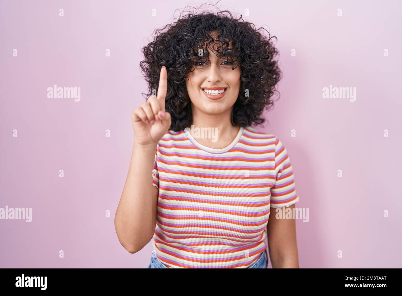 Young middle east woman standing over pink background showing and ...