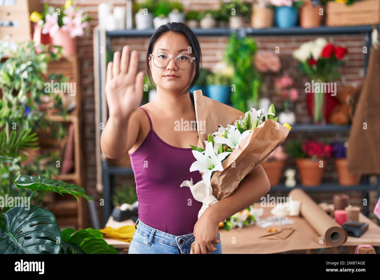 Asian young woman at florist shop holding bouquet of flowers with open ...