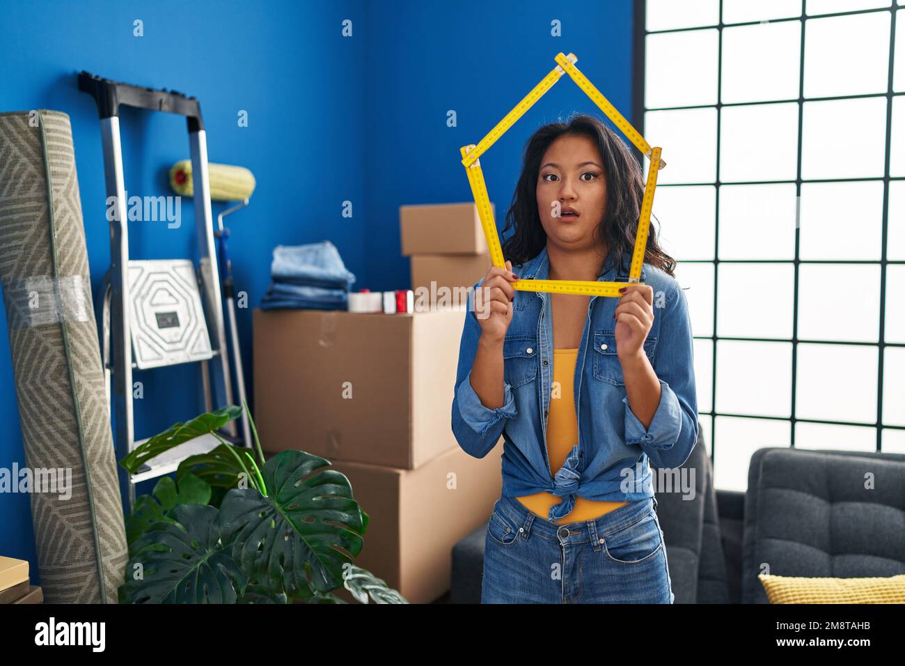 Young asian woman moving to a new home in shock face, looking skeptical ...