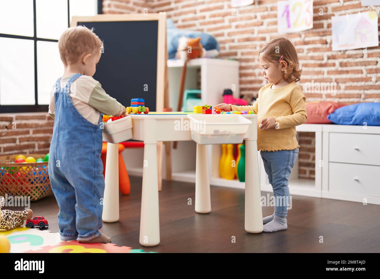 Two kids playing with construction blocks standing at kindergarten ...