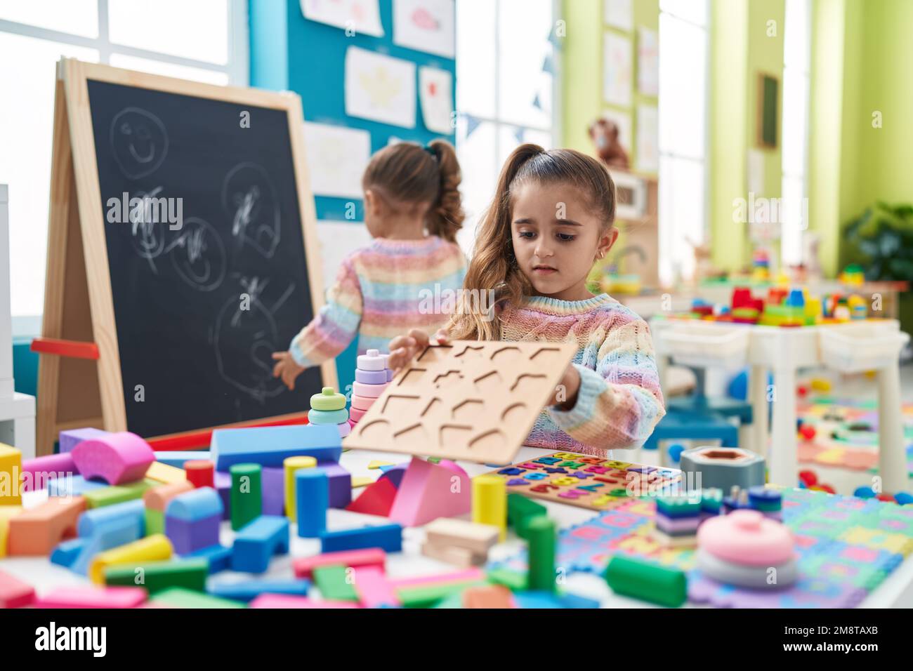 Two kids playing with maths puzzle game standing at kindergarten Stock ...