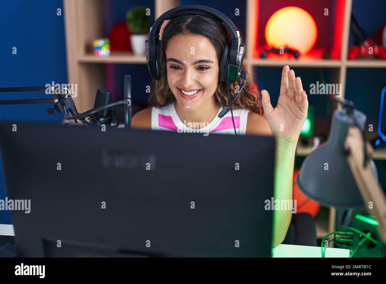 Young hispanic woman playing video games looking positive and happy ...