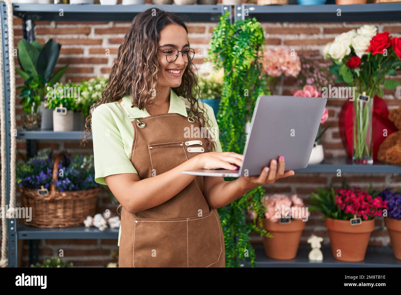 Young beautiful hispanic woman florist smiling confident using laptop ...