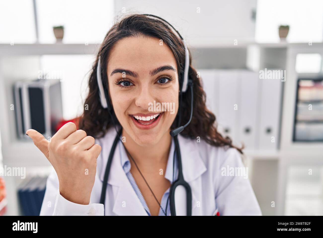 Young doctor woman working on online appointment pointing thumb up to ...