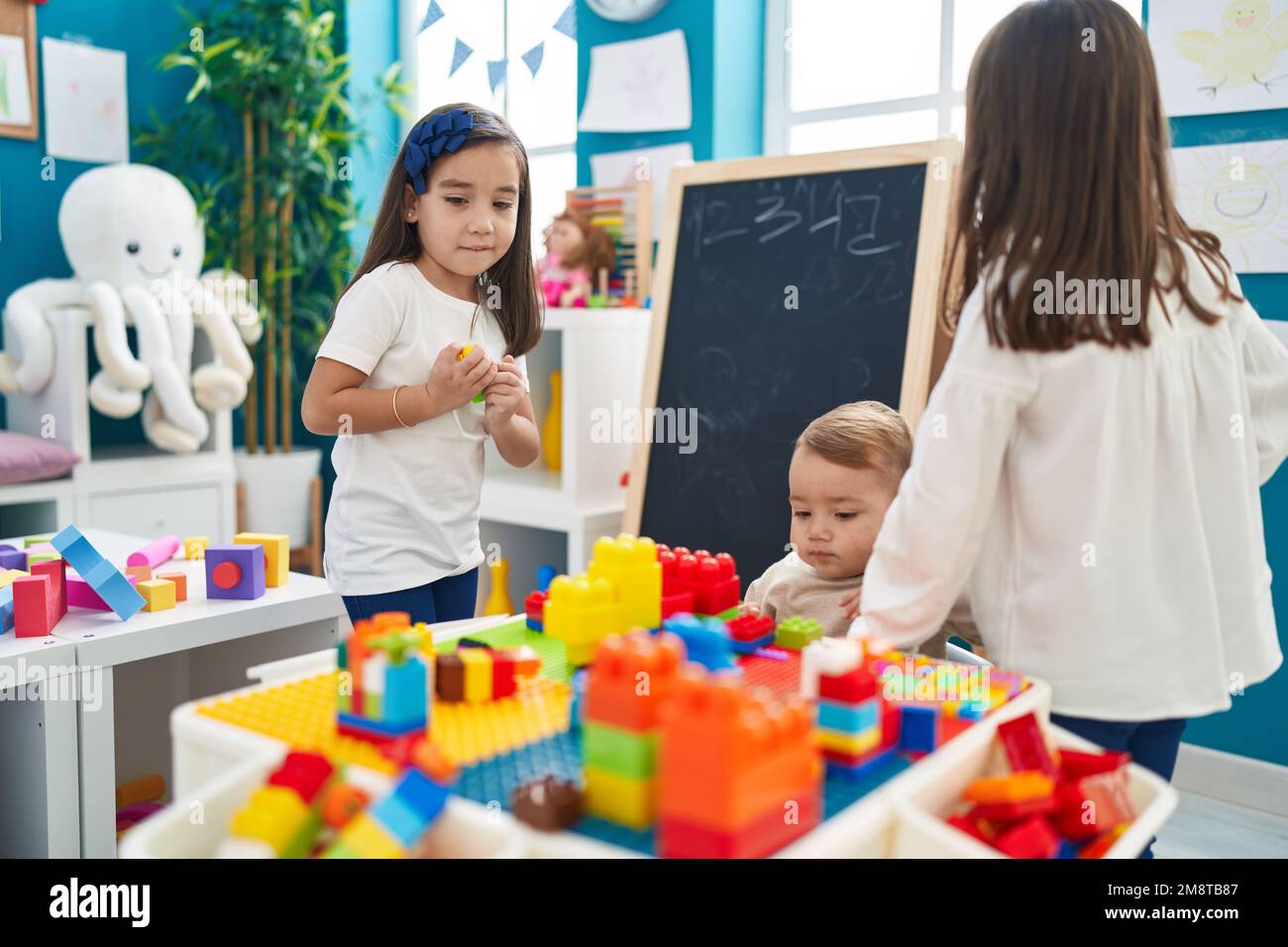 Group of kids playing with construction blocks standing at kindergarten ...