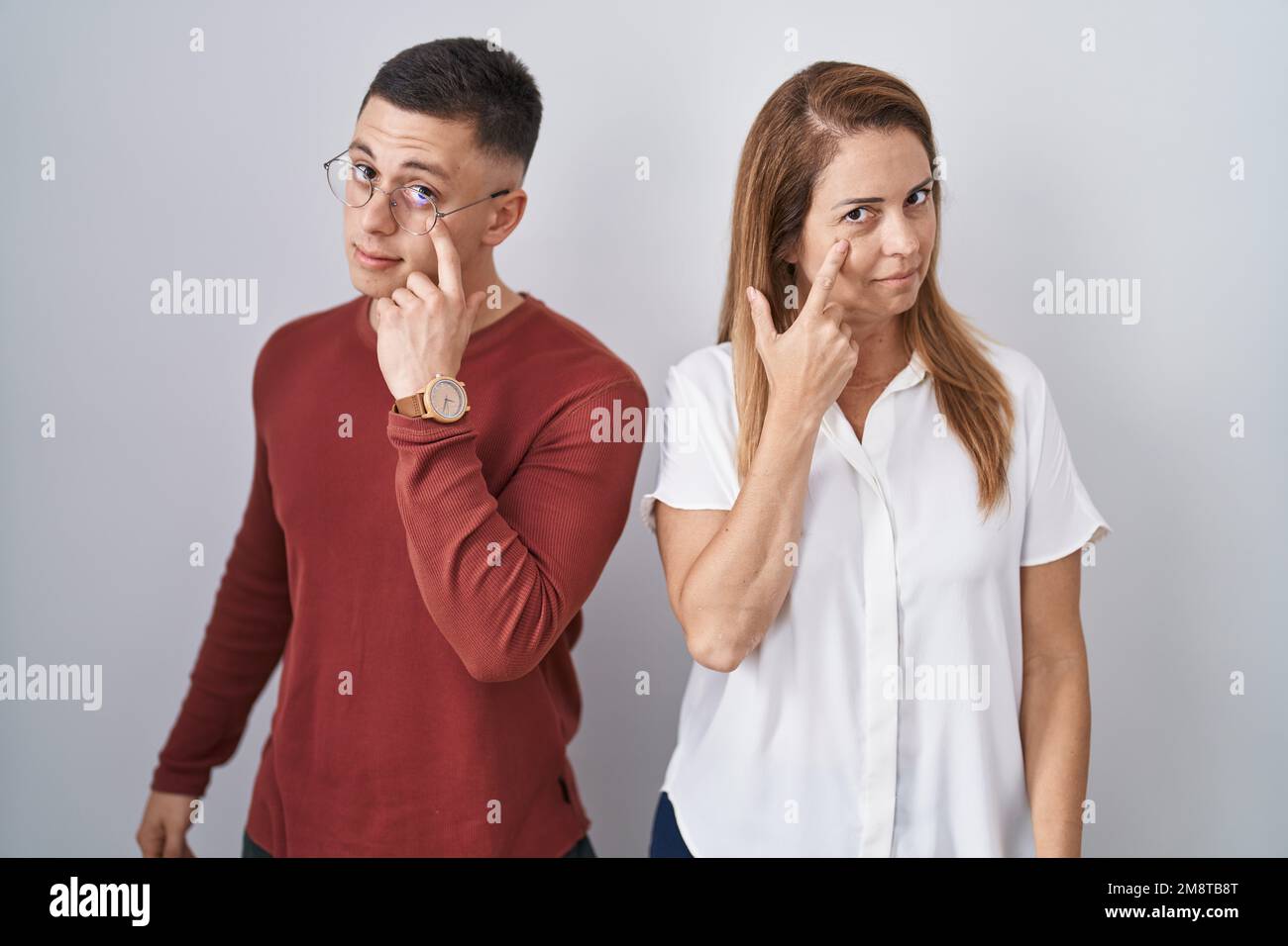 Mother and son standing together over isolated background pointing to ...