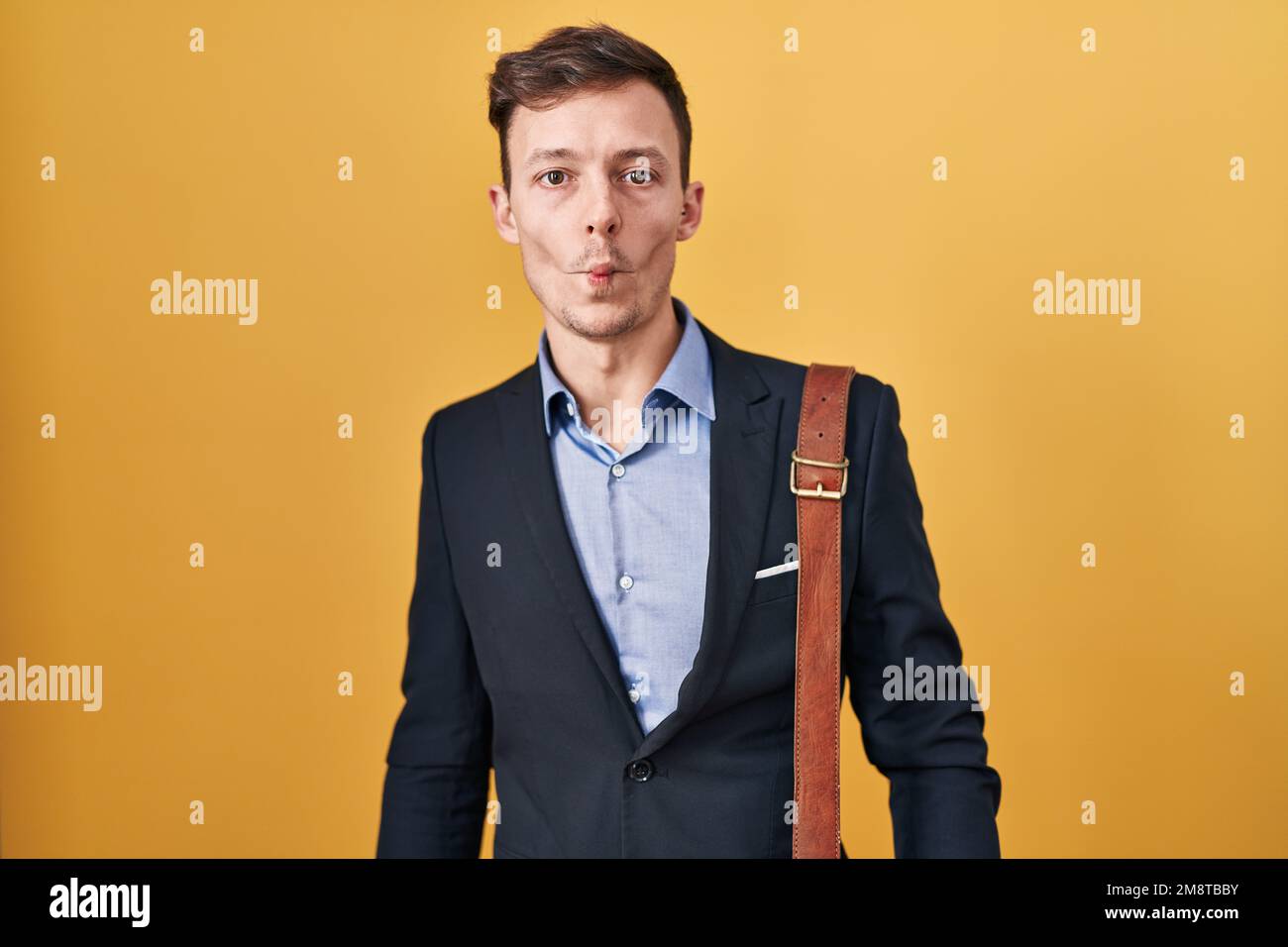 Caucasian business man over yellow background making fish face with ...