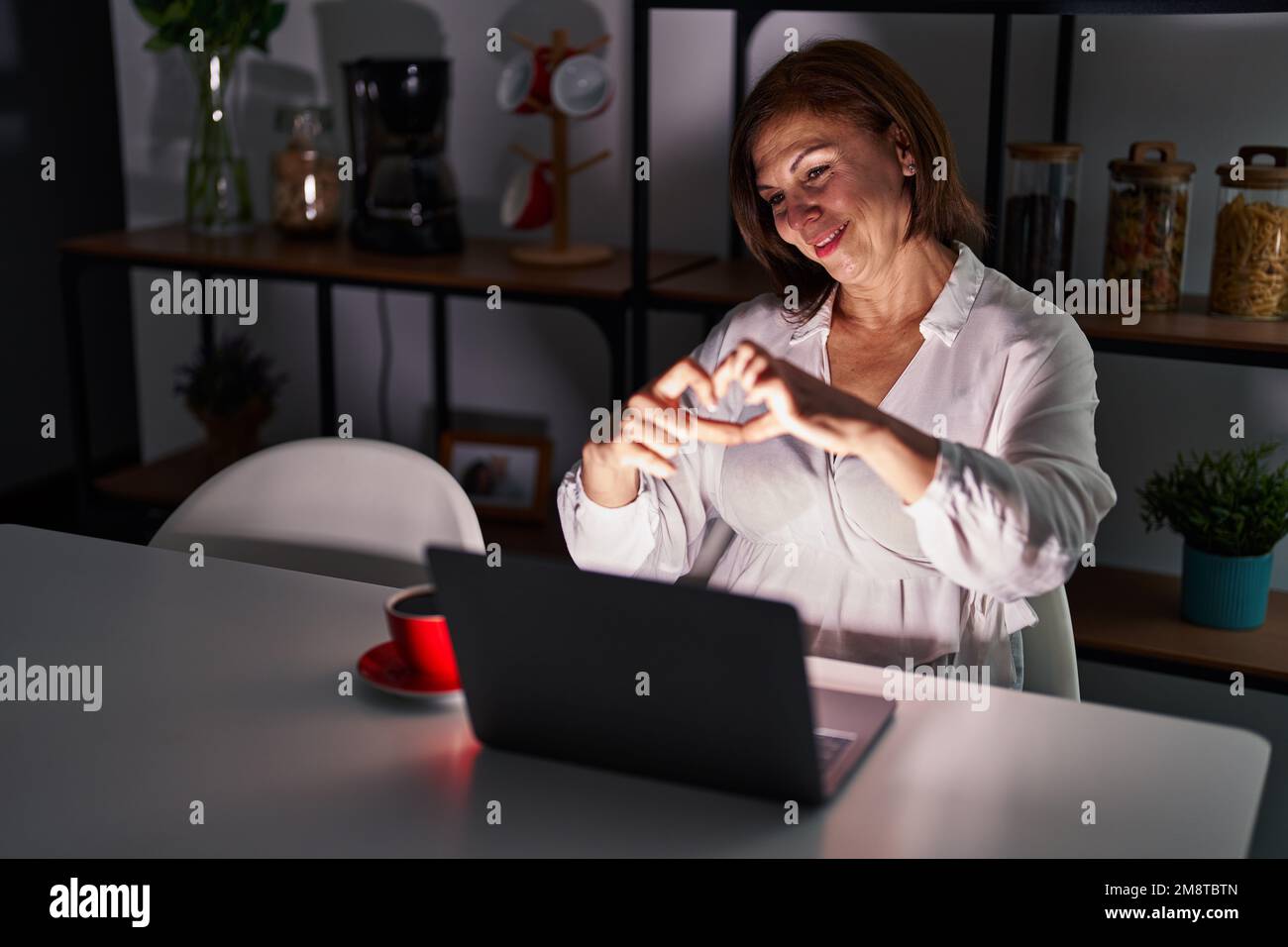 Middle age hispanic woman using laptop at home at night smiling in love ...