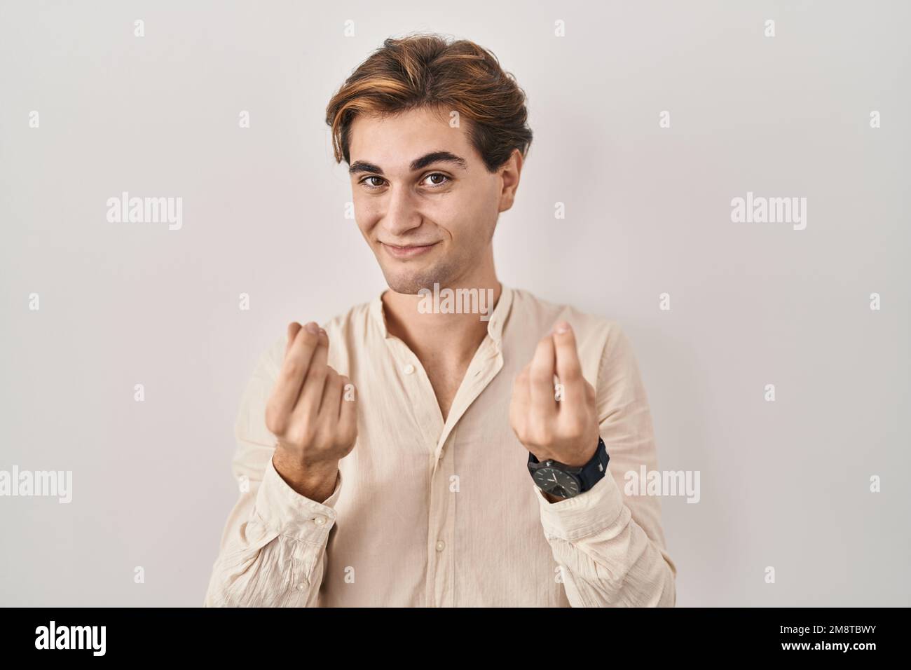 Young man standing over isolated background doing money gesture with ...