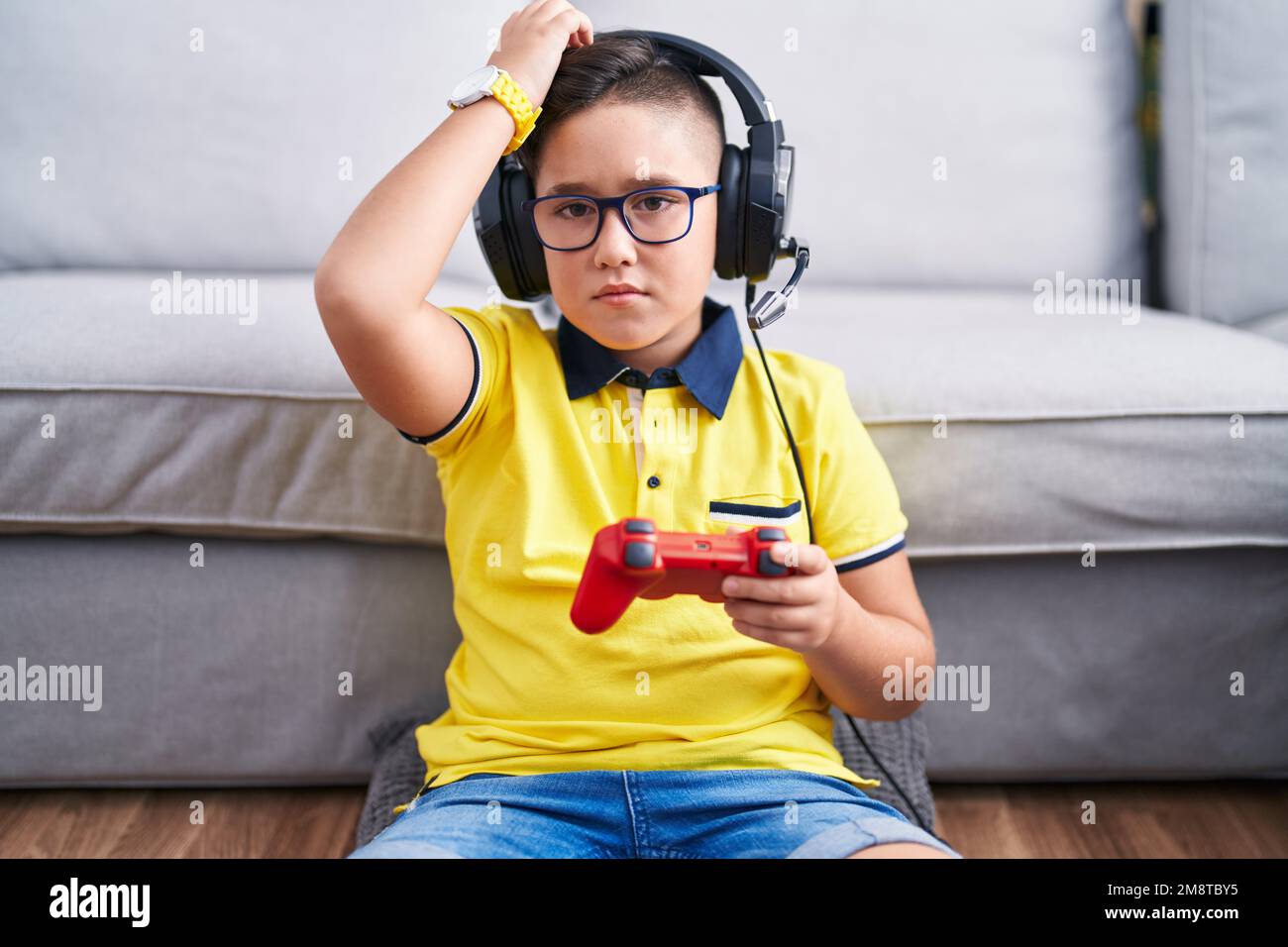 Young hispanic kid playing video game holding controller wearing ...