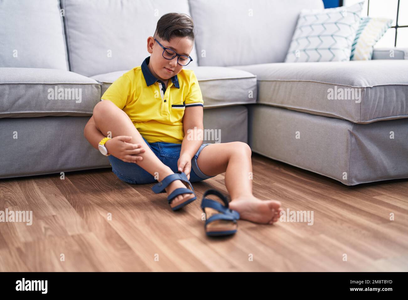 Adorable hispanic boy sitting on floor wearing slippers at home Stock ...