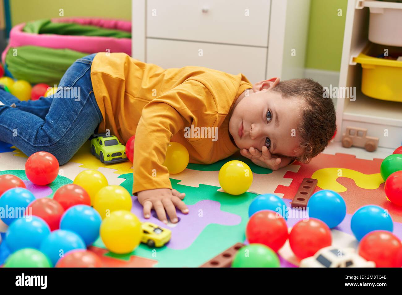 Adorable caucasian boy playing with balls lying on floor at ...