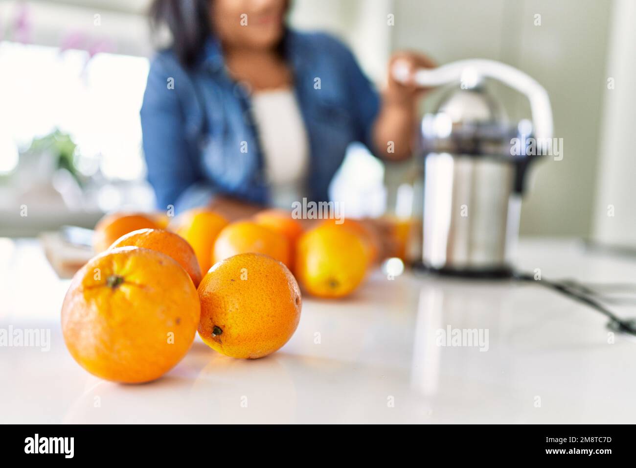 Hispanic brunette woman preparing orange juice at the kitchen Stock ...