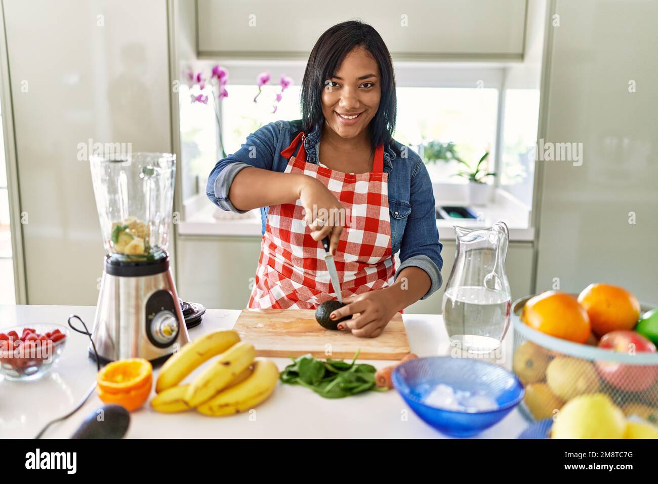Hispanic brunette woman preparing fruit smoothie at the kitchen Stock ...
