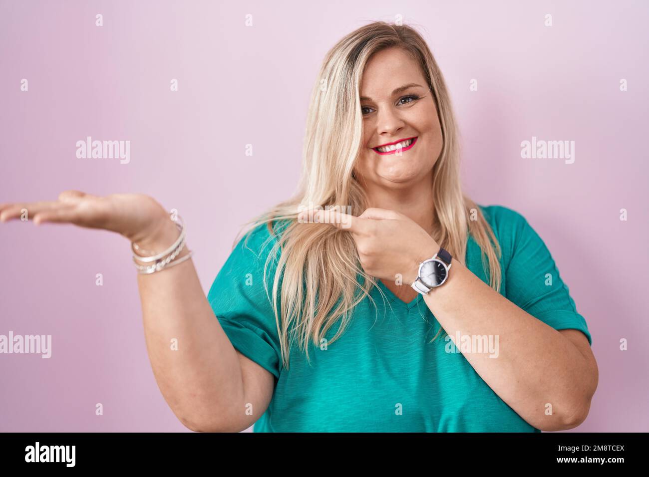 Caucasian plus size woman standing over pink background amazed and ...