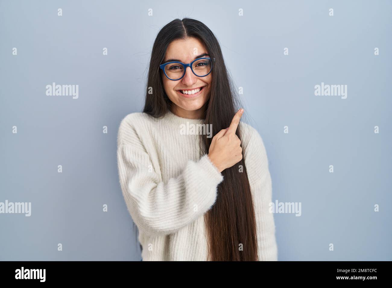 Young hispanic woman wearing casual sweater over blue background ...