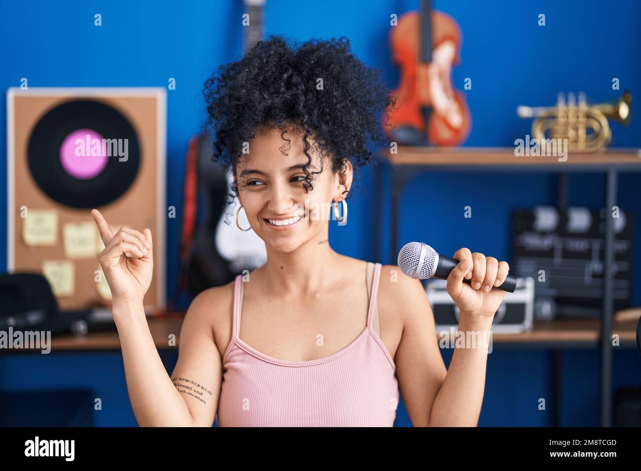Hispanic woman with curly hair singing song using microphone at music ...