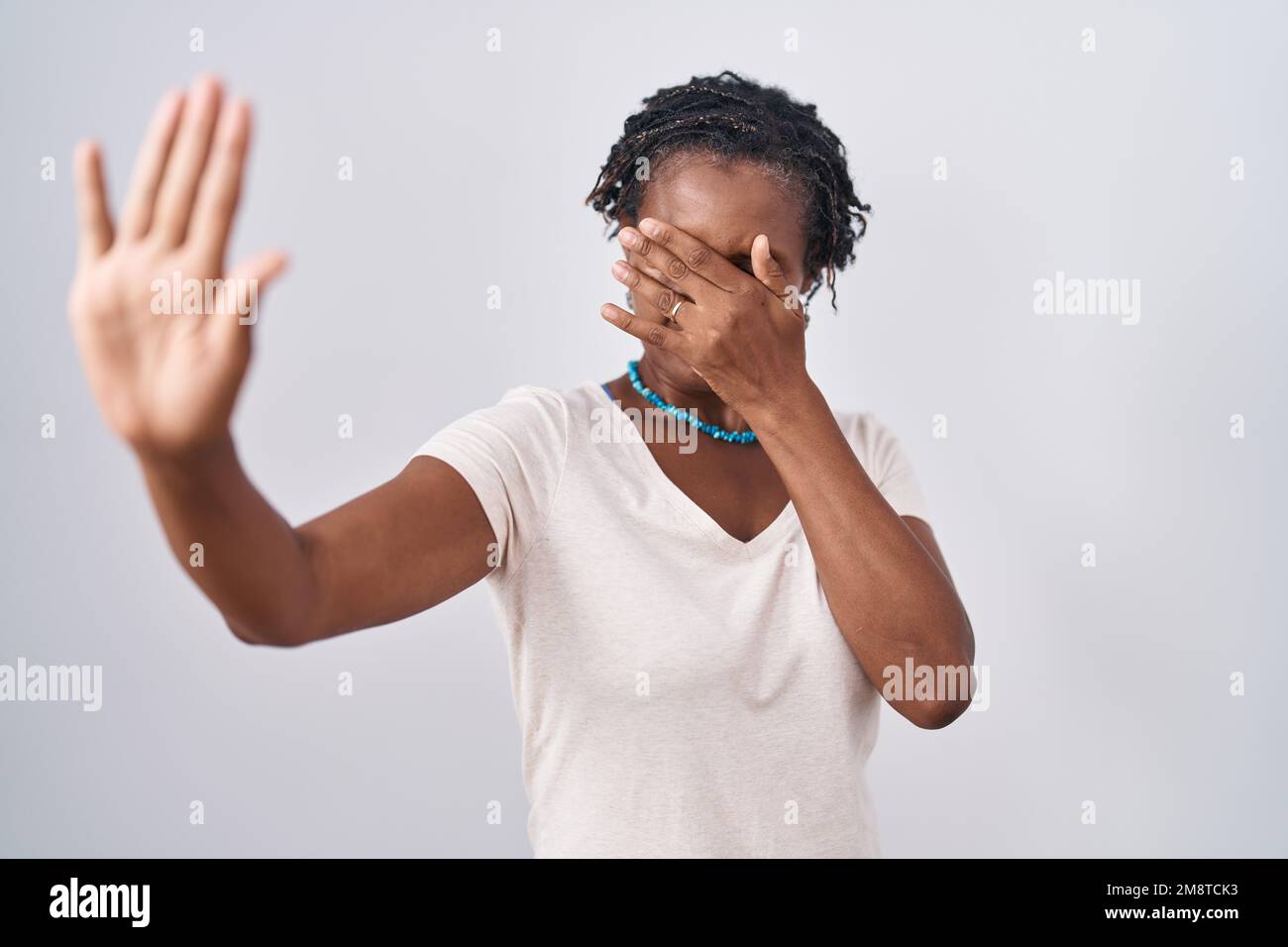 African woman with dreadlocks standing over white background covering ...