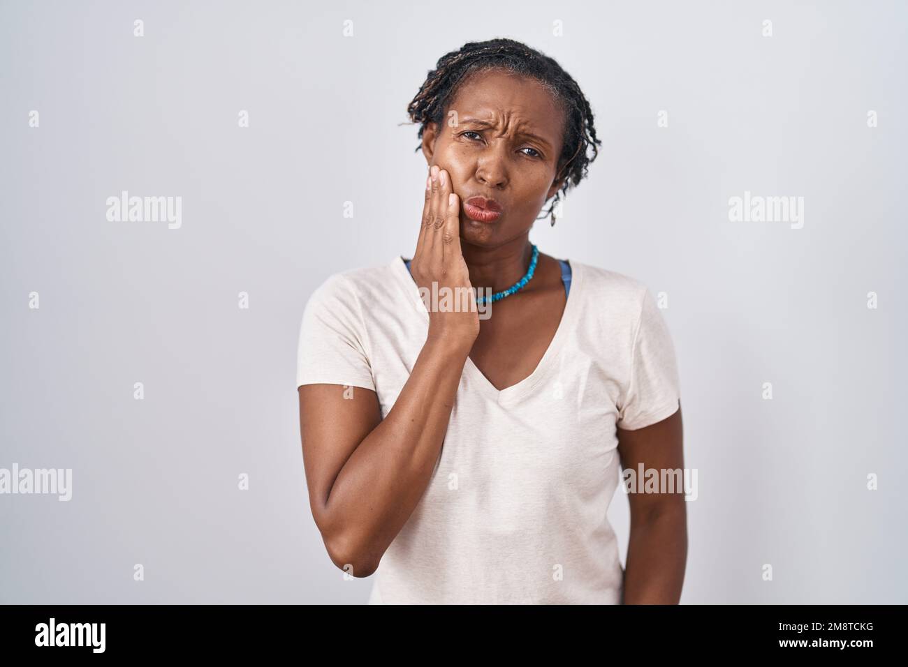 African woman with dreadlocks standing over white background touching ...