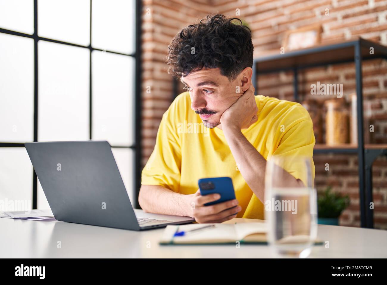 Young caucasian man using laptop and smartphone at home Stock Photo - Alamy