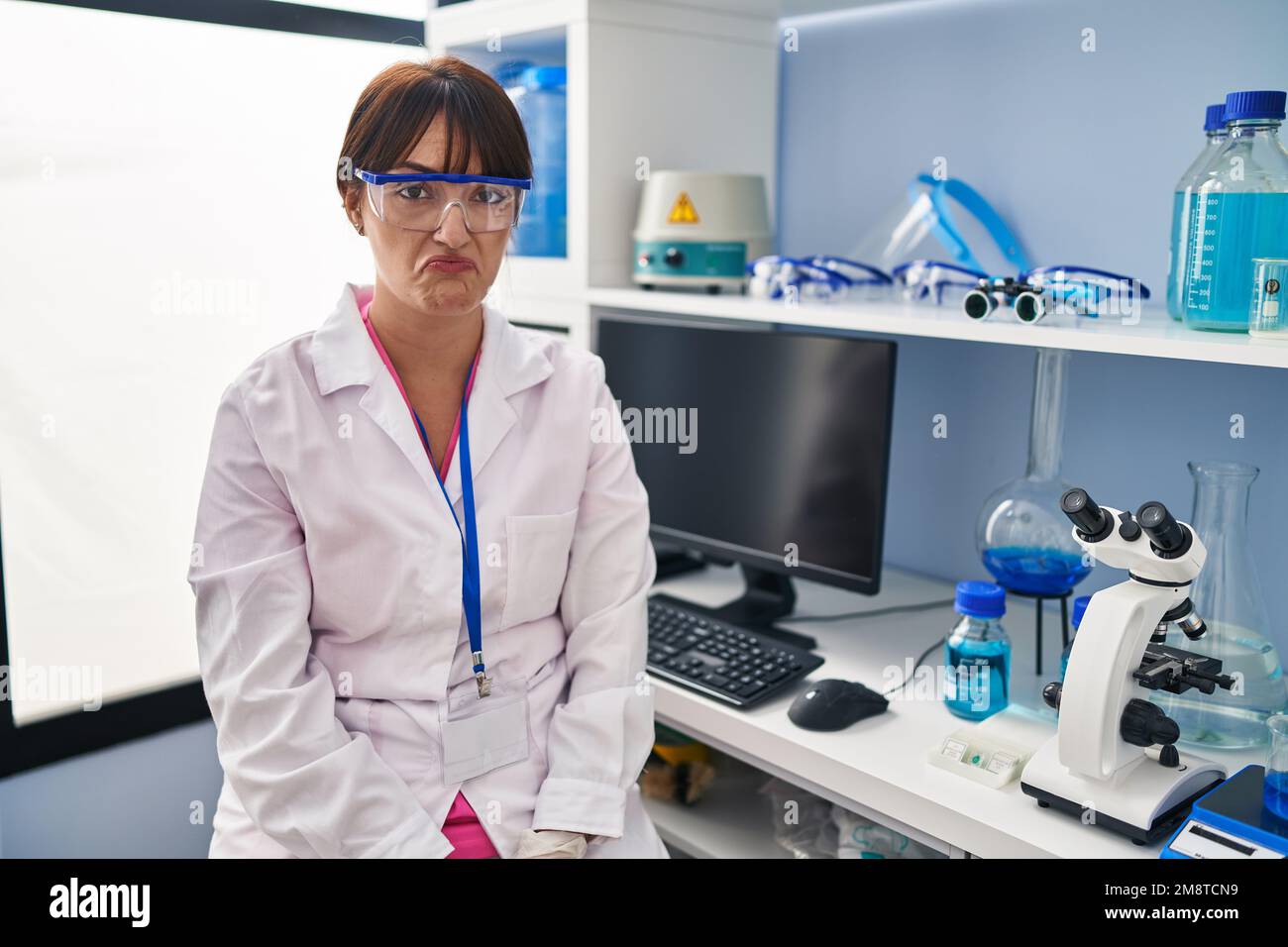 Young brunette woman working at scientist laboratory depressed and ...