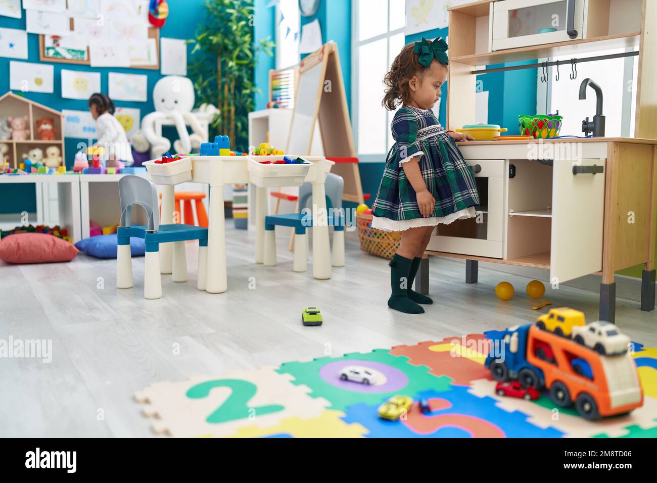 Adorable blonde toddler playing with play kitchen standing at ...