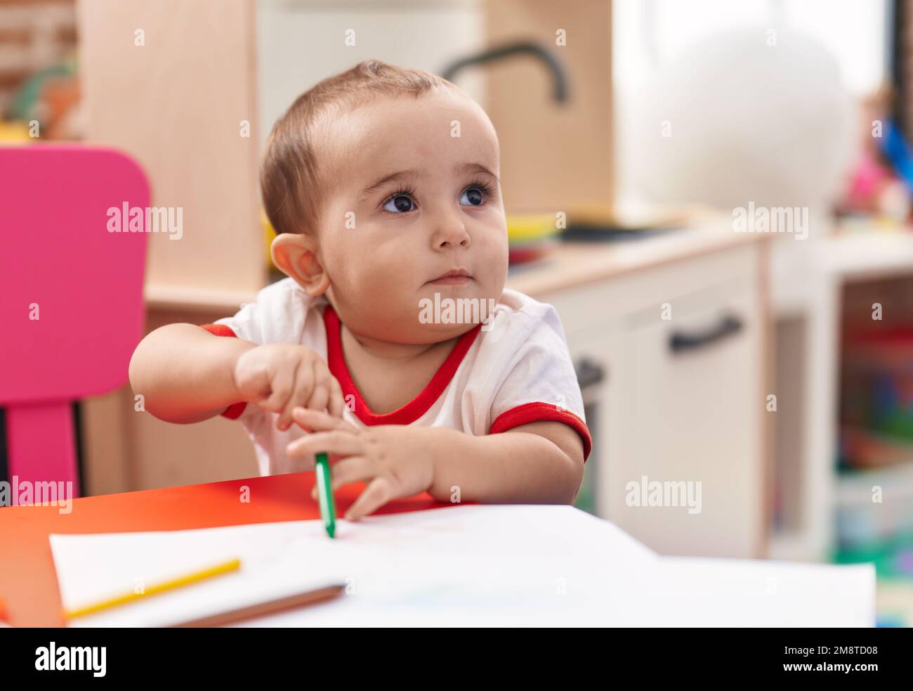Adorable hispanic baby preschool student drawing on notebook standing ...