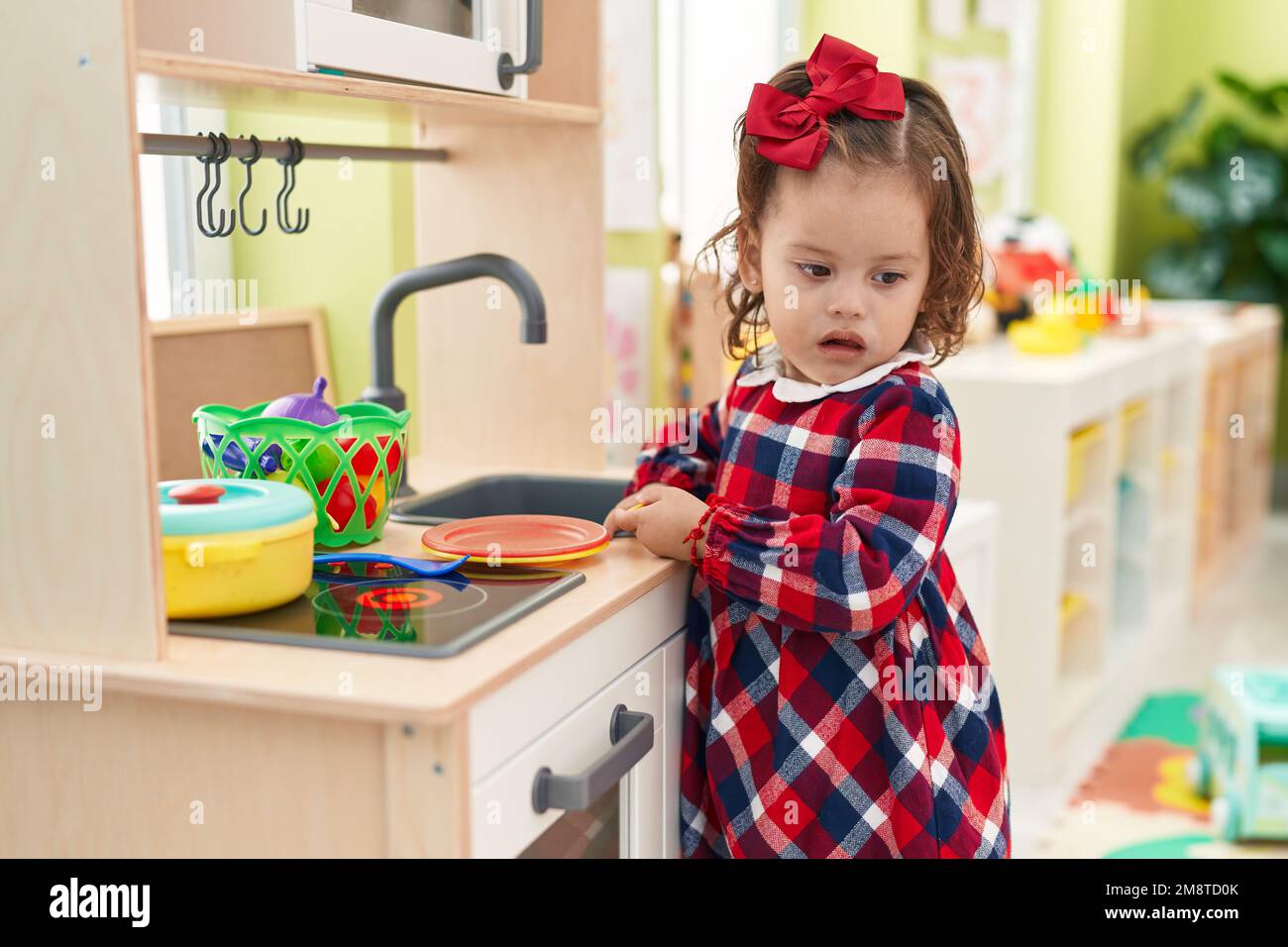 Adorable blonde toddler playing with play kitchen standing at ...