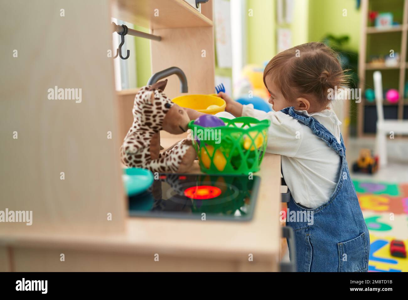 Adorable blonde toddler playing with play kitchen standing at ...