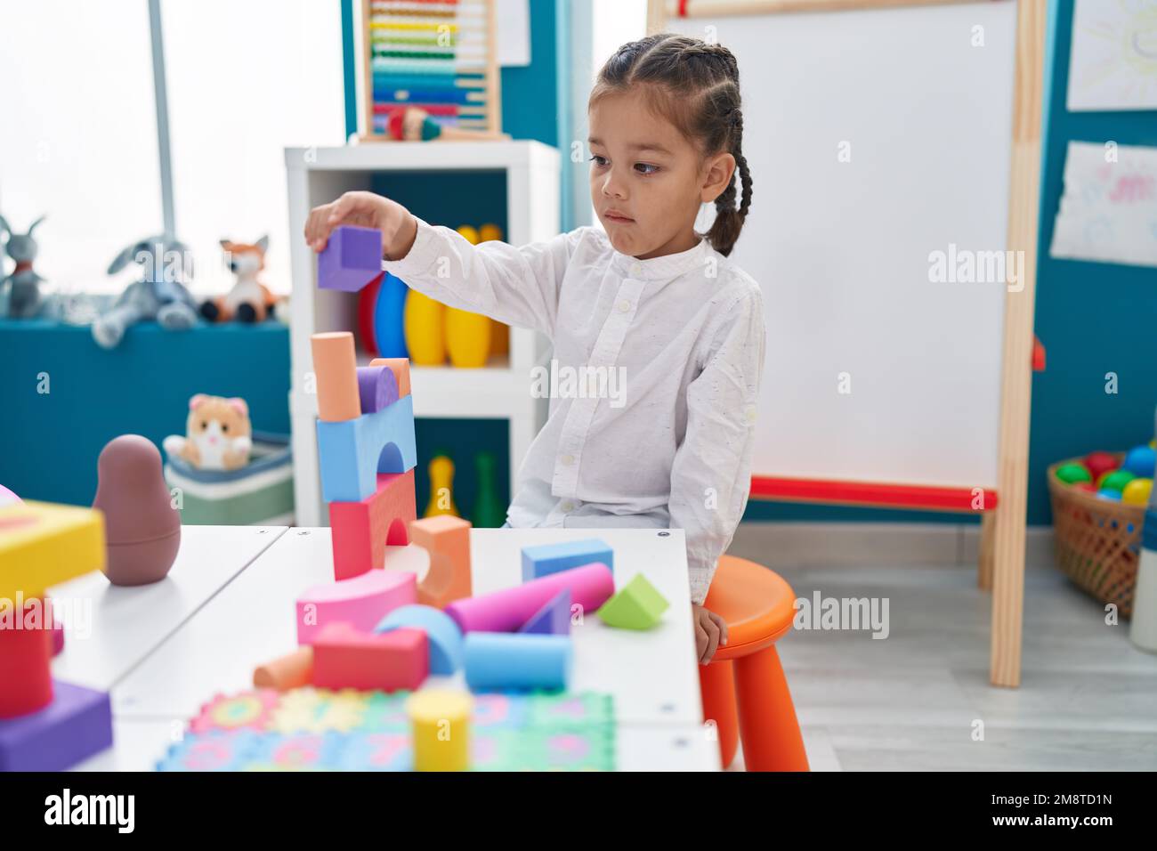 Adorable hispanic boy playing with construction blocks standing at ...