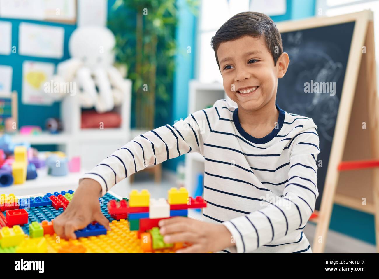 Adorable hispanic boy playing with construction blocks sitting on table ...